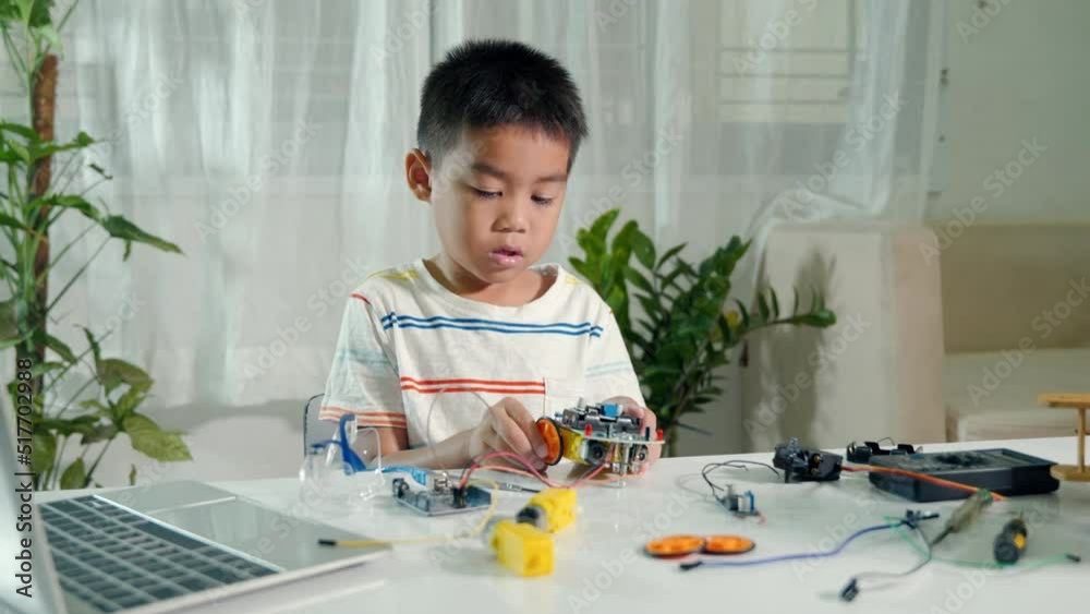 Asian kid boy assembling wheel into Arduino robot car homework, Little ...