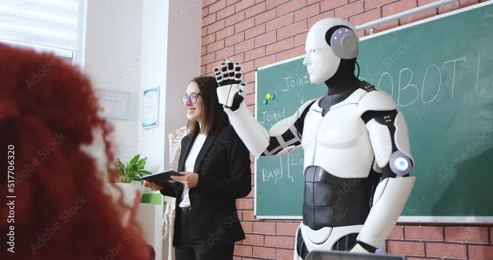 Vidéo Stock Caucasian happy female teacher standing at blackboard and showing robot humanoid to ...