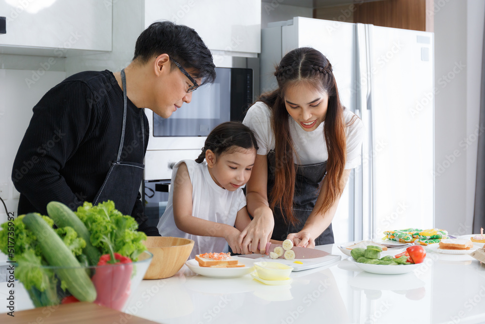 Happy family cooking together in the kitchen. Father, mother, and cute ...