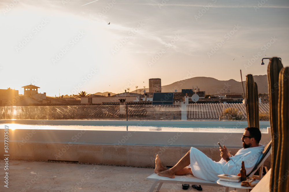 Young guy chilling on deckchair at poolside on rooftop Stock Photo ...