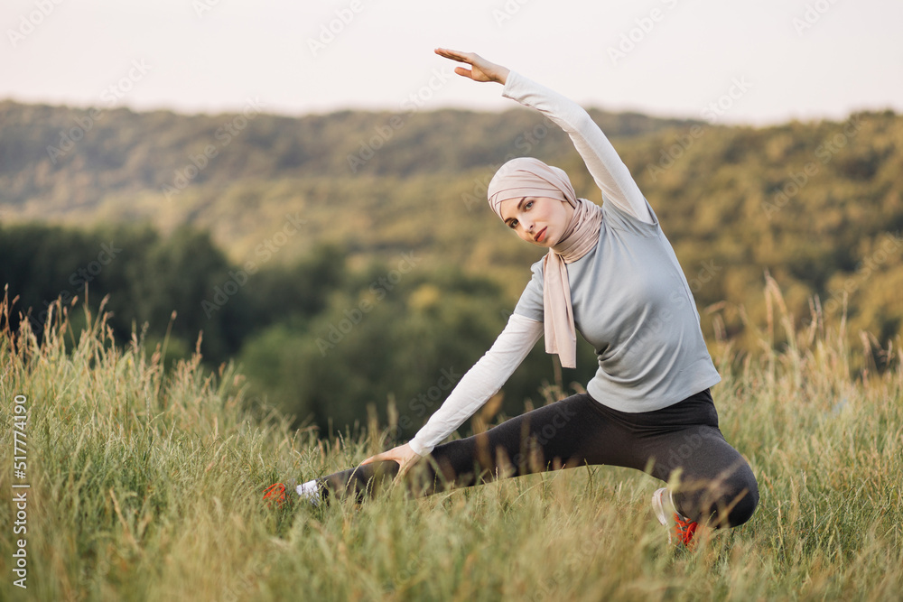 Outdoor sports concept. Athletic young Muslim woman in sportswear doing ...