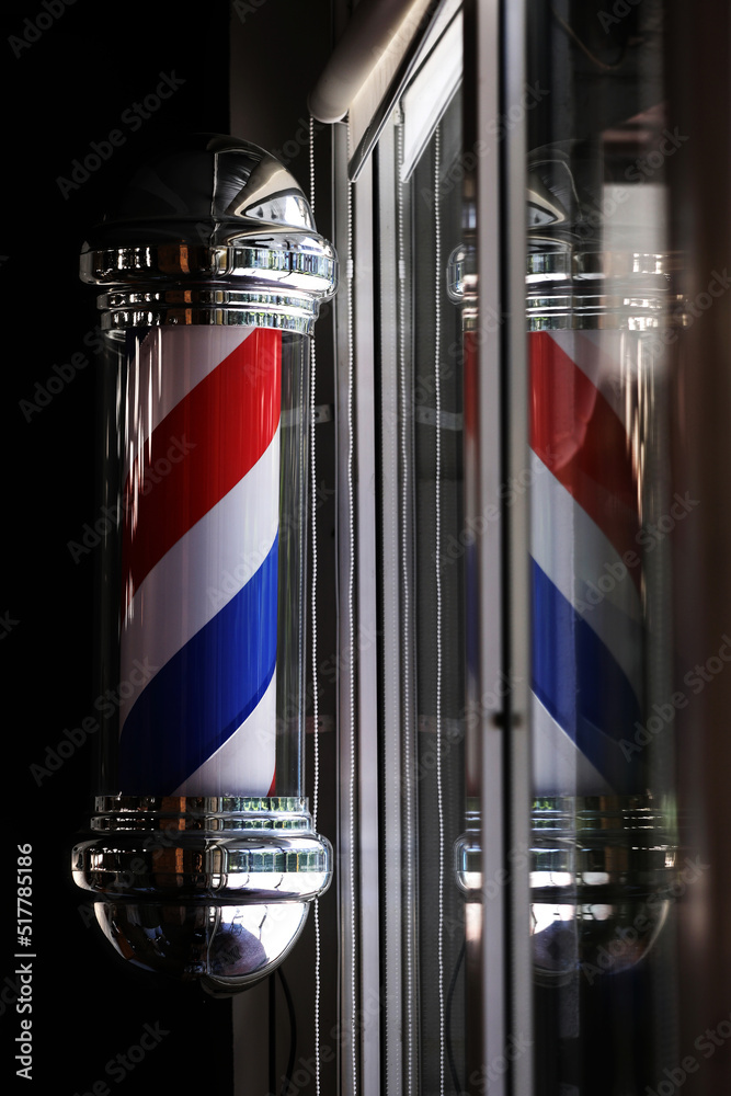 Barber pole spinning at night. International barbershop pole sign. A ...