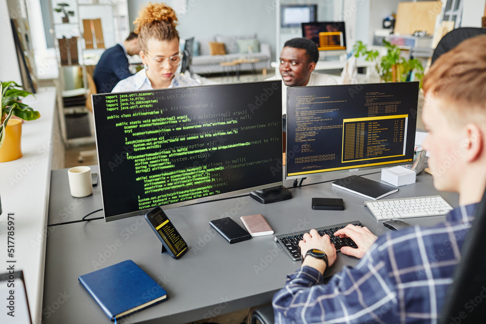 Multiethnic IT specialist working with program on monitors at office ...