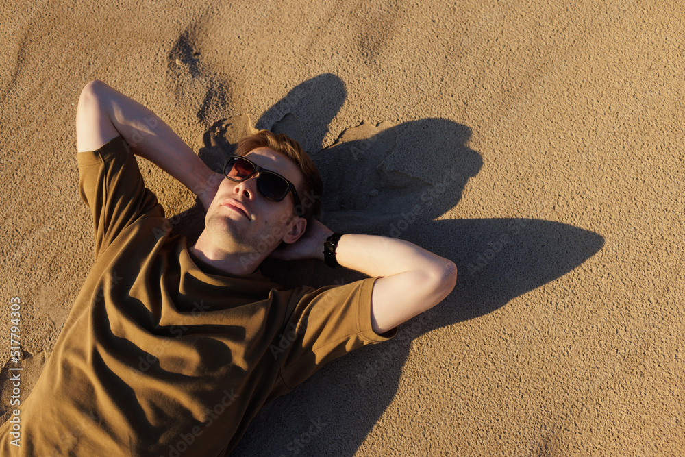 Young man laying in beach sand. People fatigue from sunburn and work ...