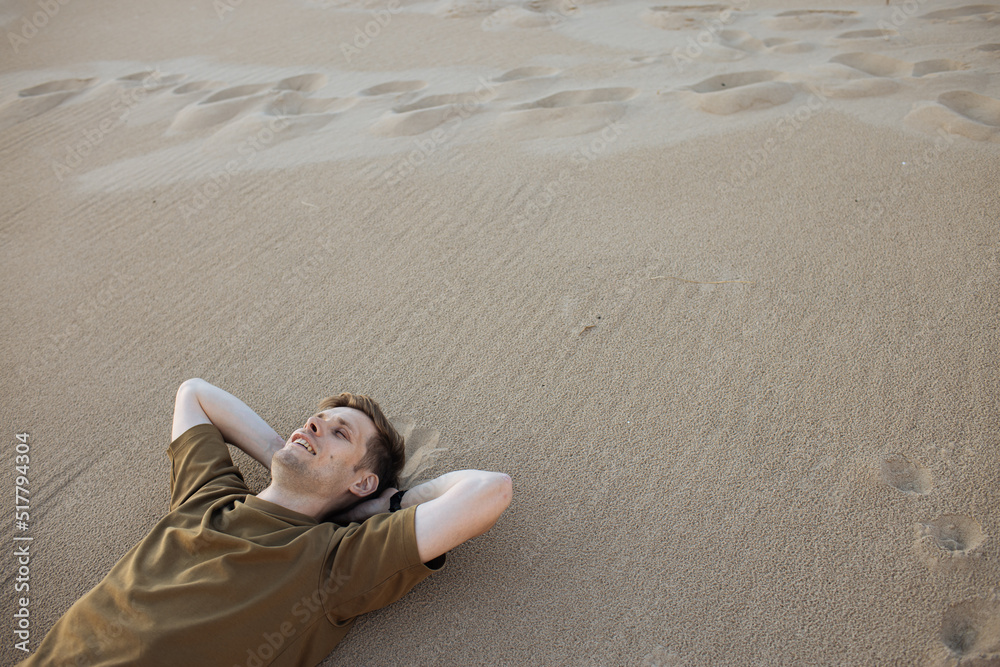 Young man laying in beach sand. People fatigue from sunburn and work ...