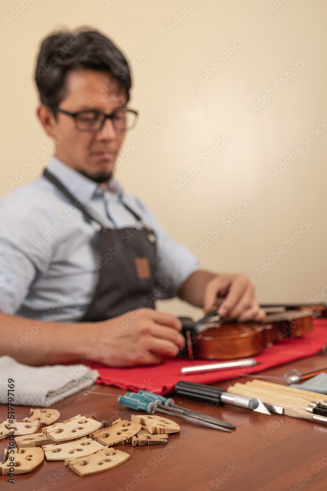 Tools to repair an instrument next to violin bridges on a workshop ...
