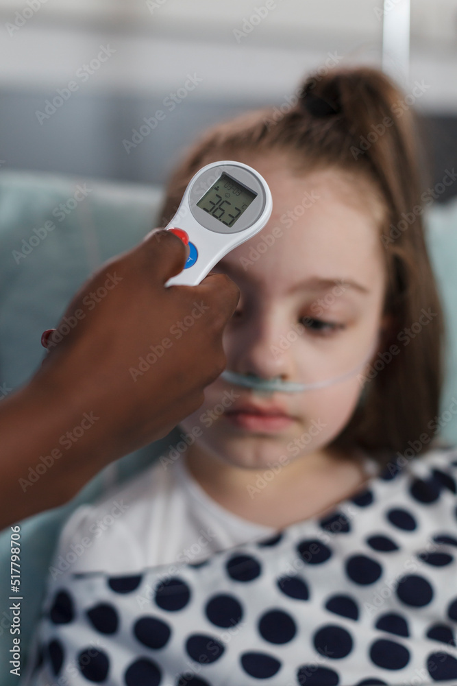 Close up shot of pediatric hospital nurse measuring sick little girl ...