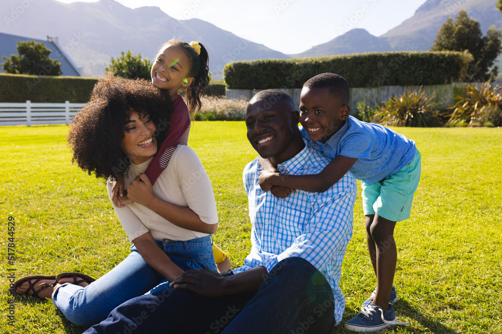 Happy multiracial children cuddling mother and father from behind ...