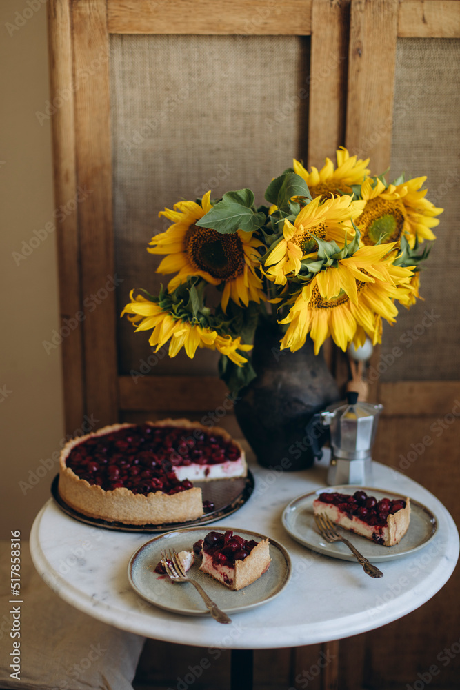 sunflower bouquet in a vase on a round table with cherry cheesecake ...