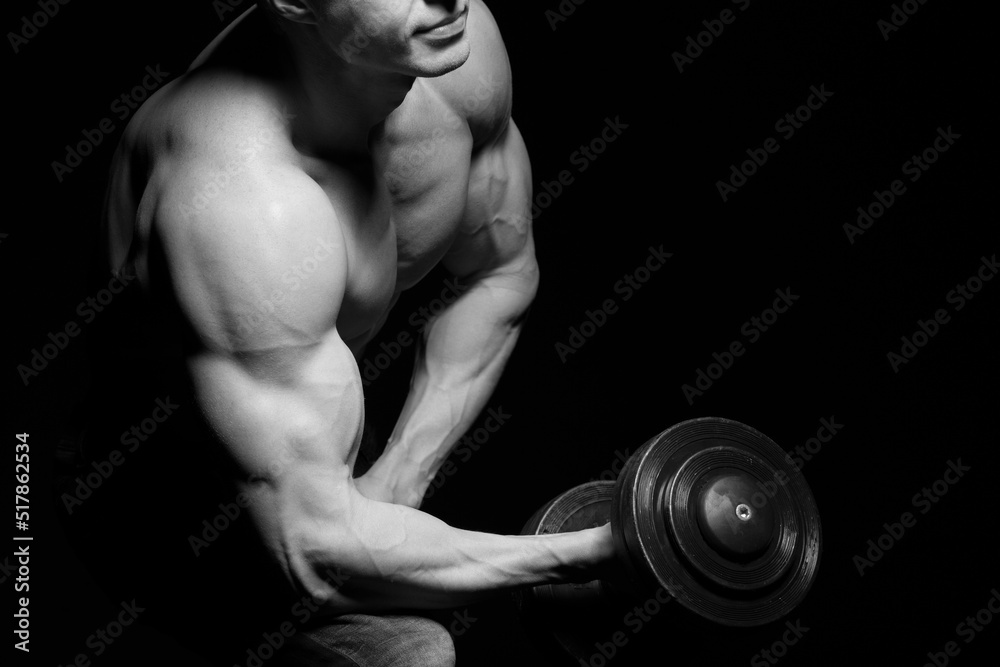 Handsome power athletic man with dumbbell confidently looking forward ...