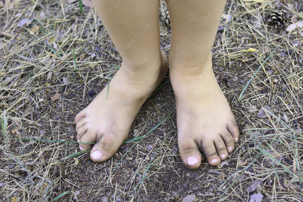 Feet of child in summer on ground without shoes on feet as symbol of ...