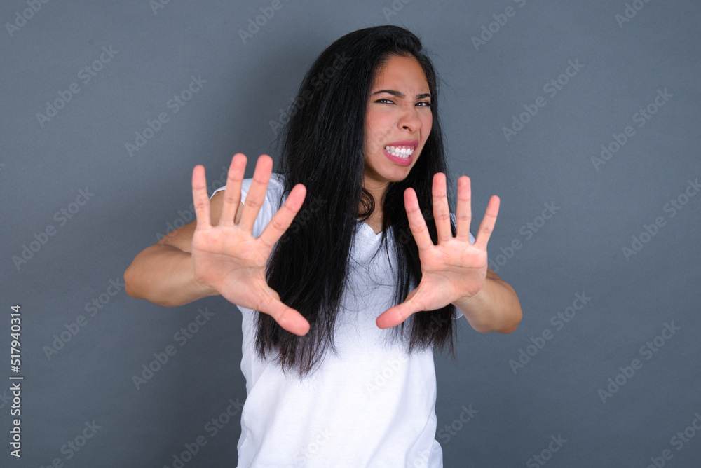 Dissatisfied young beautiful brunette woman wearing white t-shirt over ...