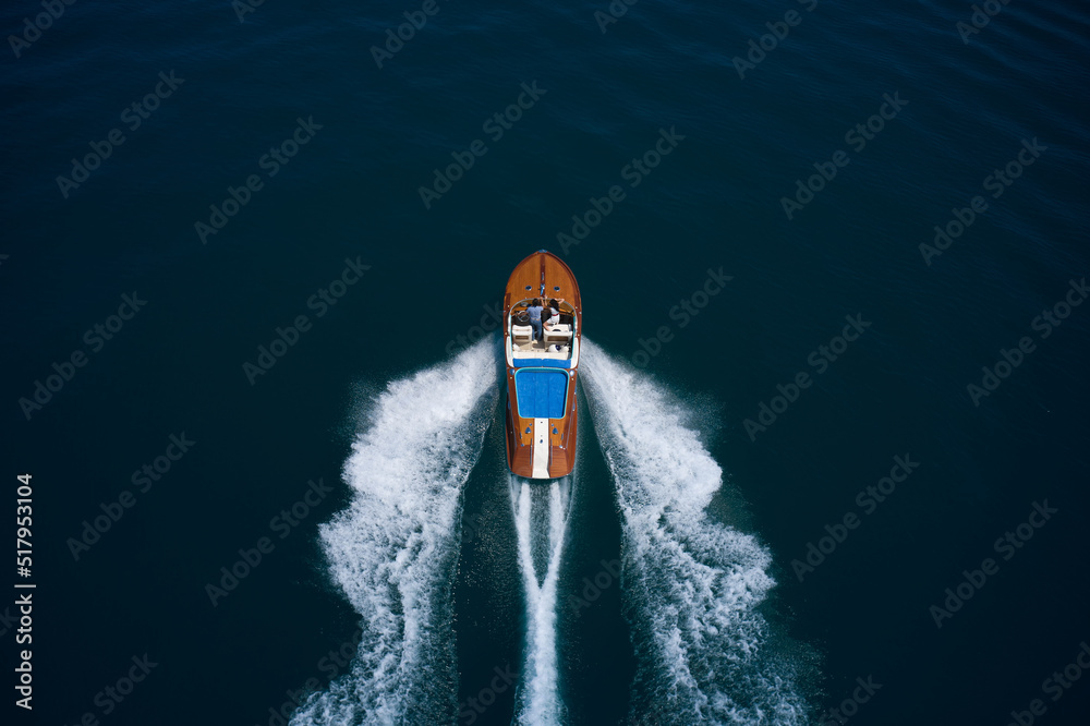High speed open modern wooden boat moving fast on dark water aerial ...