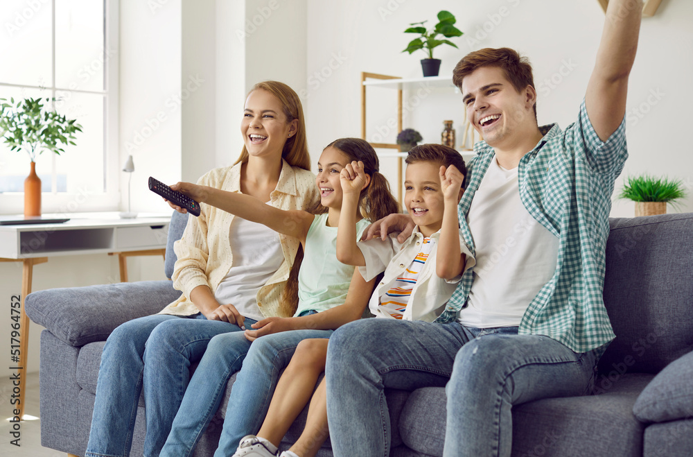 Happy family watching TV all together. Cheerful, joyful mother, father ...