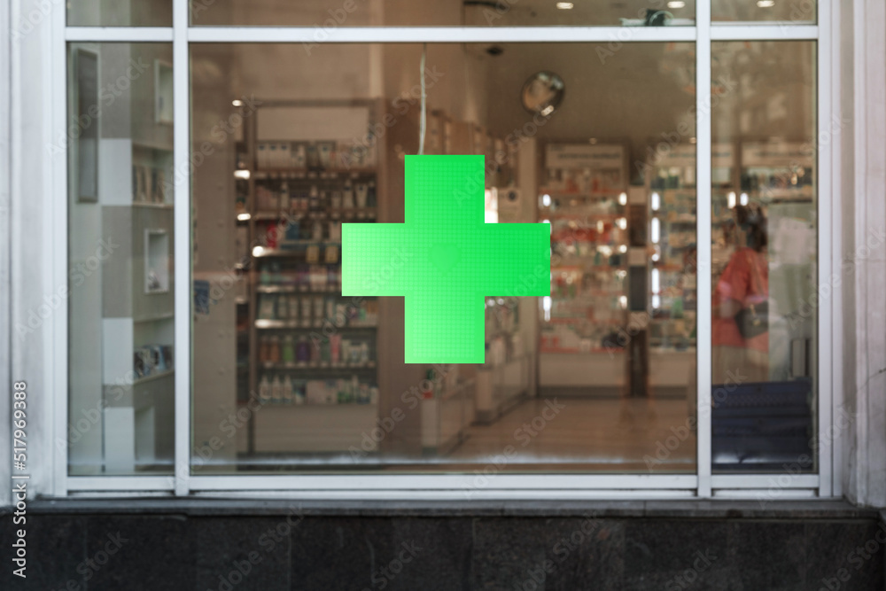Green cross sign with neon light mounted on pharmacy shop window case ...