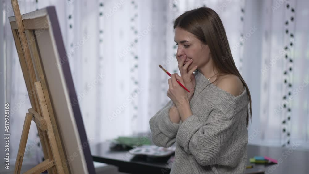 Sad beautiful painter making mistake painting on canvas standing at ...