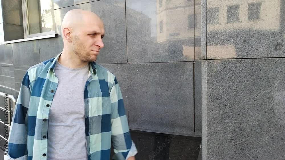 Angry young man hits the wall of building with his fist. Frustrated guy ...