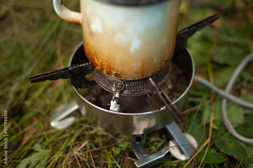 Cup of steel on fire. Tea on hike. Drink in woods. Cooking on gas ...