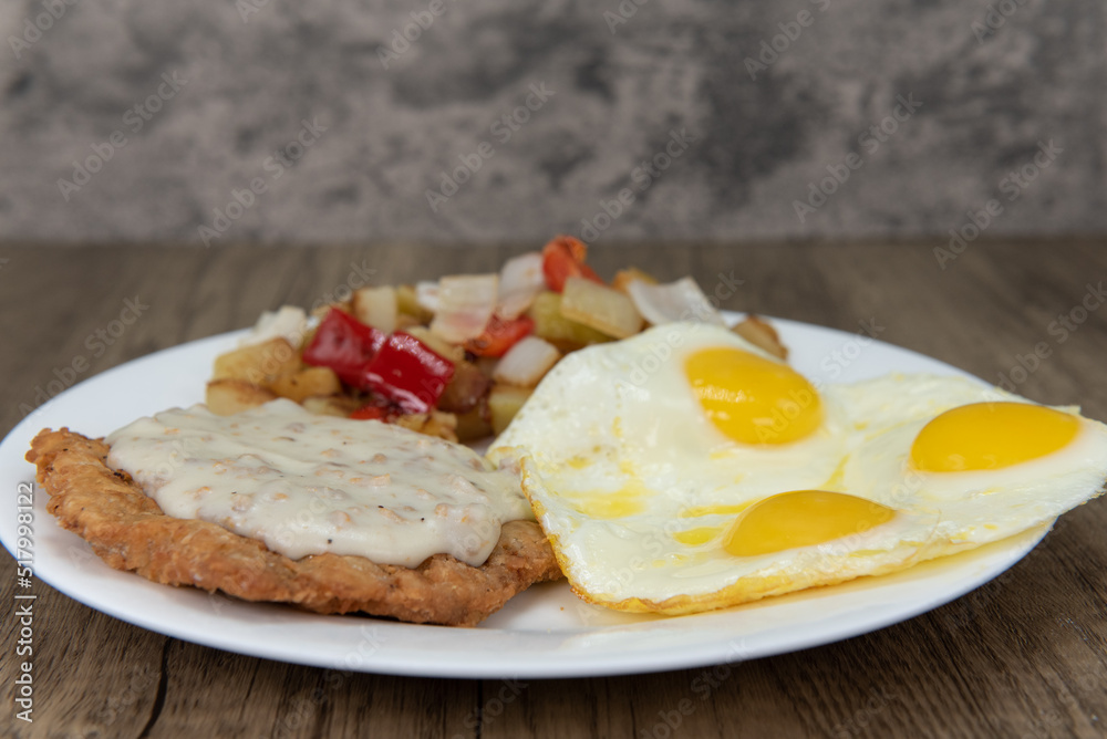 Standard American breakfast consisting of chicken fried steak, covered ...