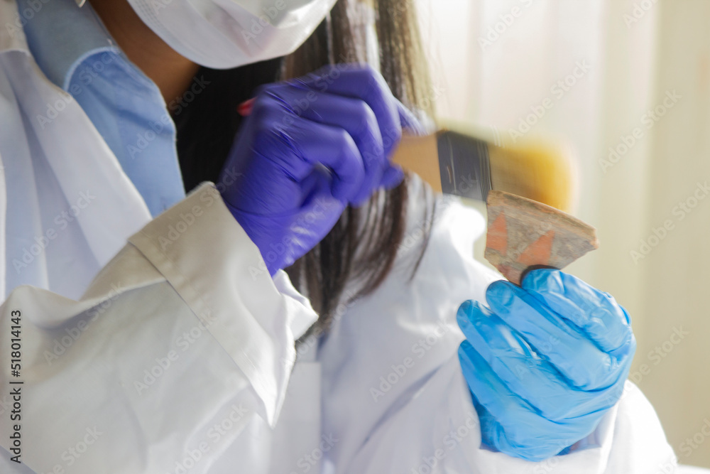 Curator and archaeologist cleaning a pottery shard found in an ...