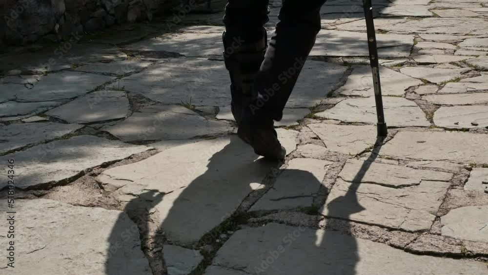 Vidéo Stock A man walks along the road leaning on a crutch and limping ...