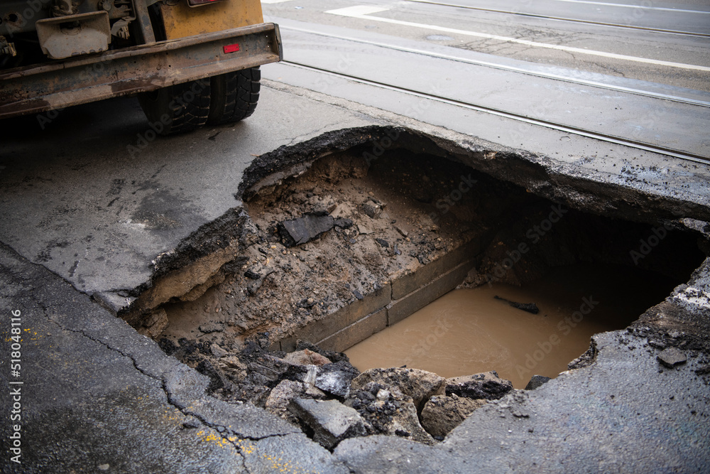 Huge sinkhole on busy asphalt road surface on which cars drive ...