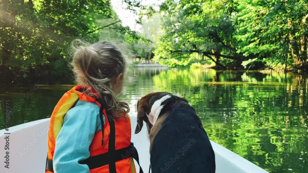 Girl child and her pet beagle dog are floating down a river on a boat ...