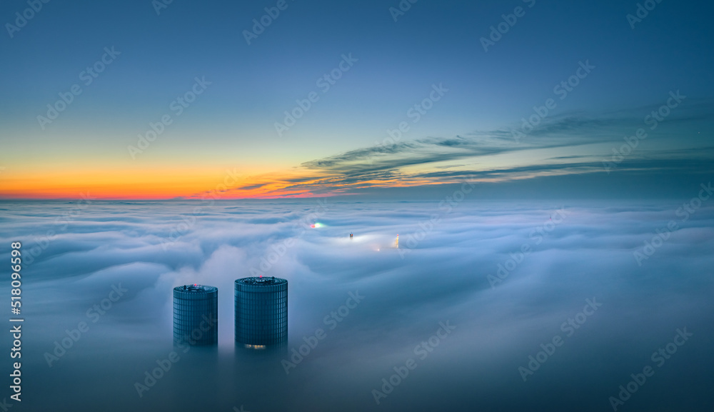 Skyscraper rooftop over the clouds at sunrise. Thick fog covers the ...