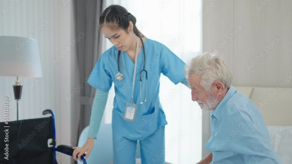 Female nurse assisting senior man to get up from bed. Caring nurse supports patient while ...