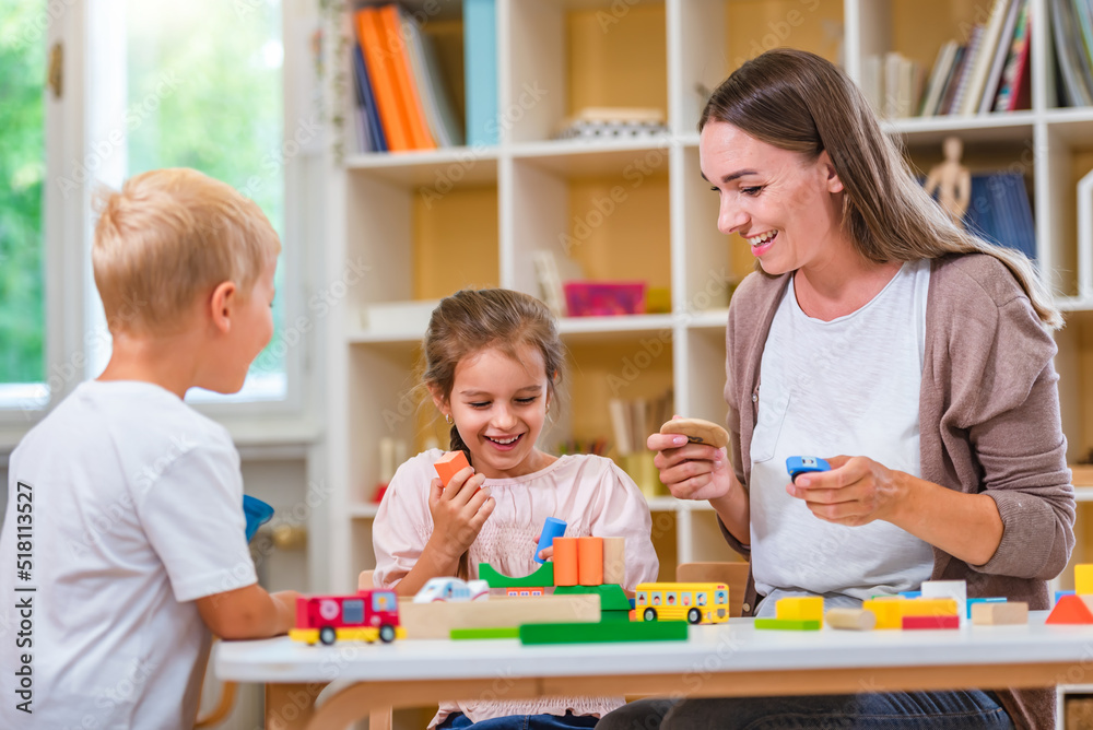 Kindergarten teacher playing together with children in the colorful ...