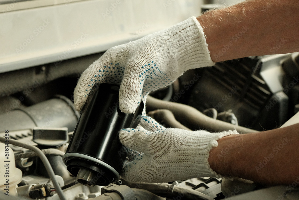 Foto de The car mechanic performs the work of replacing the oil filter ...