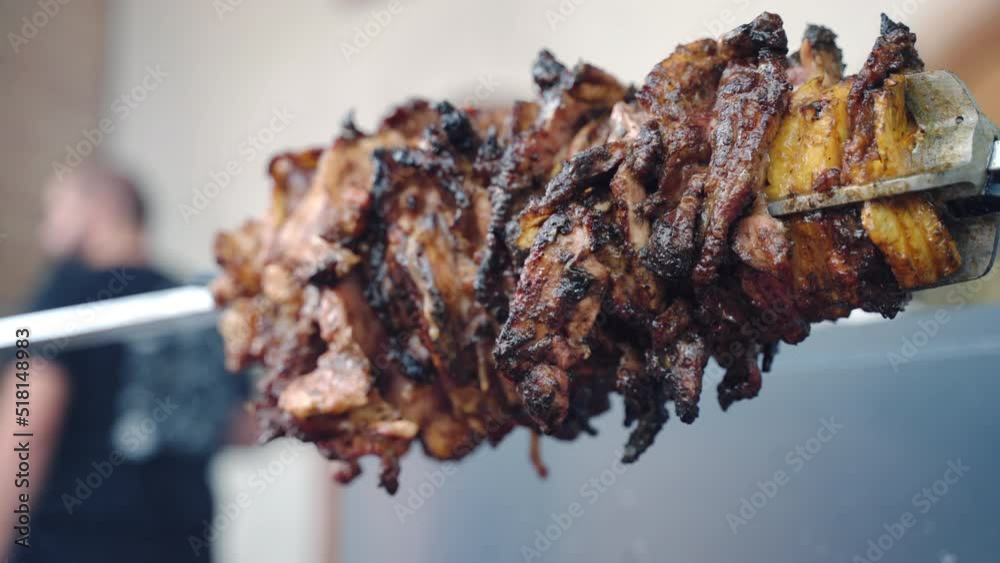 Seasoned meat delicacy roasting on fire, juicy pork pieces rotating on ...