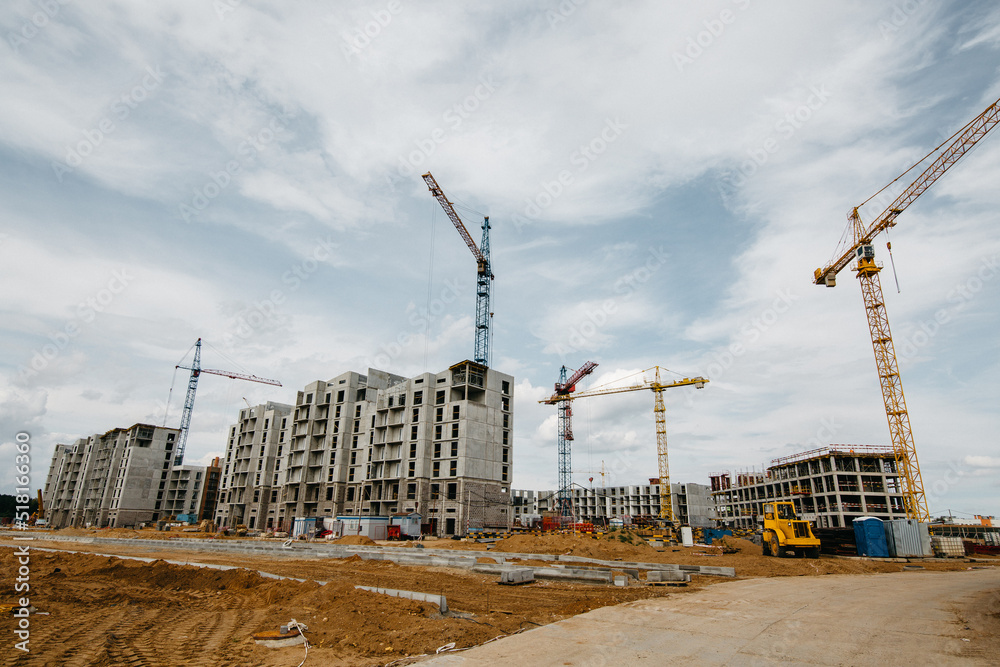 unfinished apartment buildings at the construction site and cranes in ...