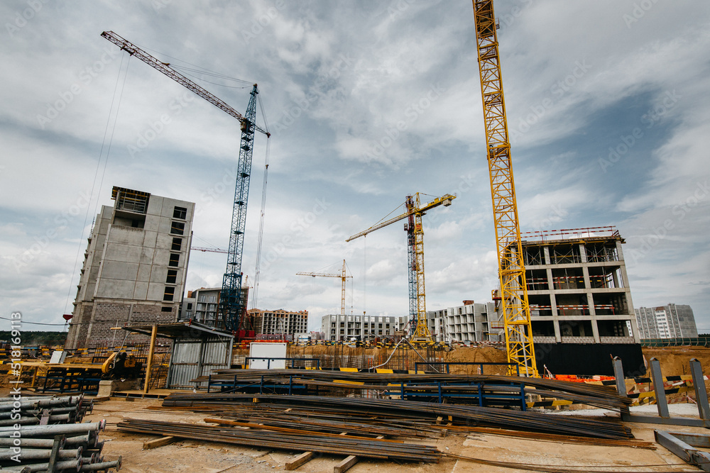 unfinished apartment buildings at the construction site and cranes in ...
