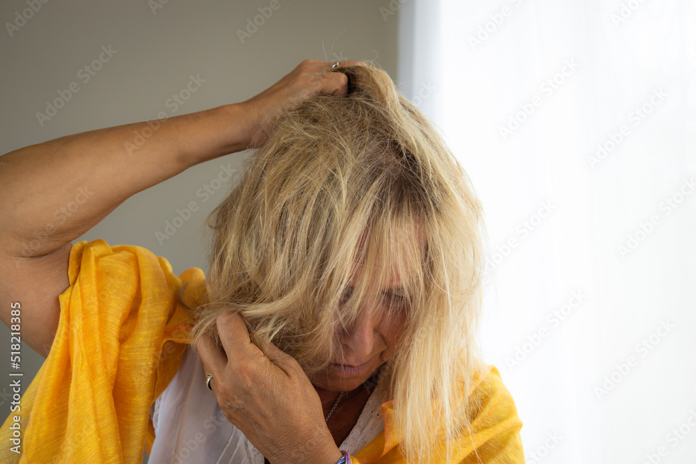 Blond woman in her 50s ruffling her hair. Concept of mental illness ...