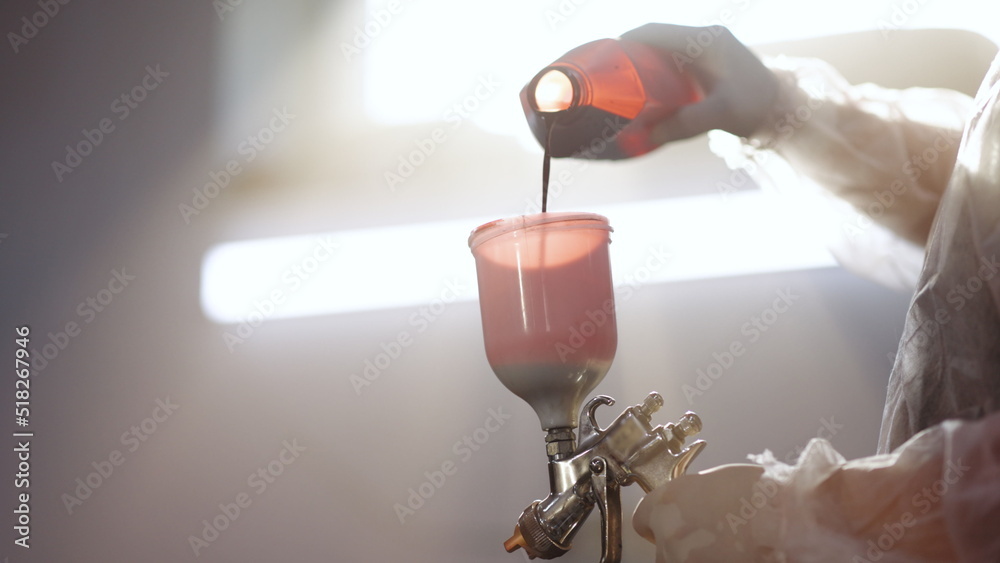 Paint-spraying gun is getting used by the worker to colour the car. Car ...