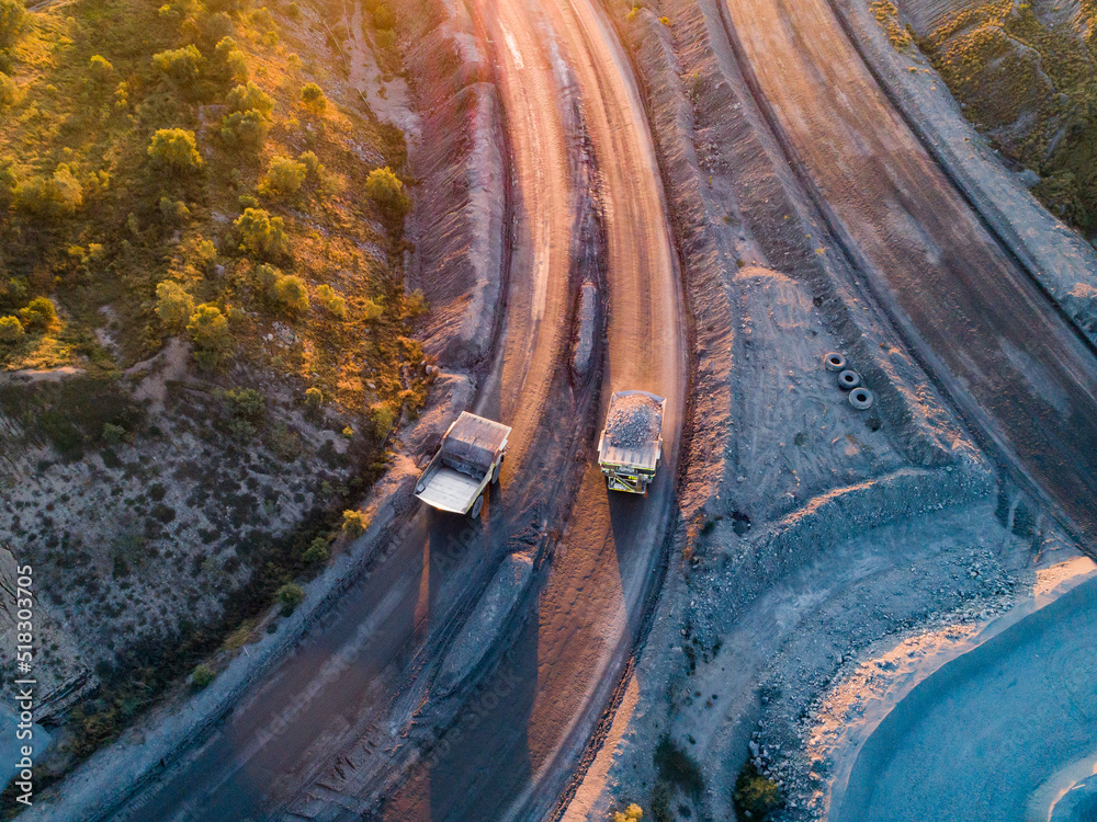 Aerial view of full and empty dump trucks passing one another in open ...
