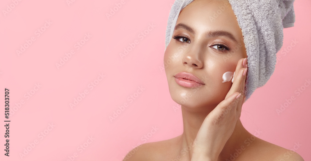 Seductive female model applies cream on cheek at pink wall Stock Photo ...