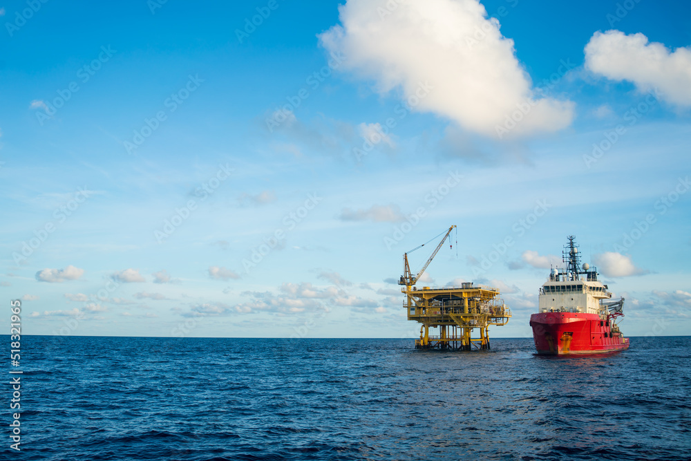 A tugboat anchors near an oil rig at an oil well to transport necessary ...
