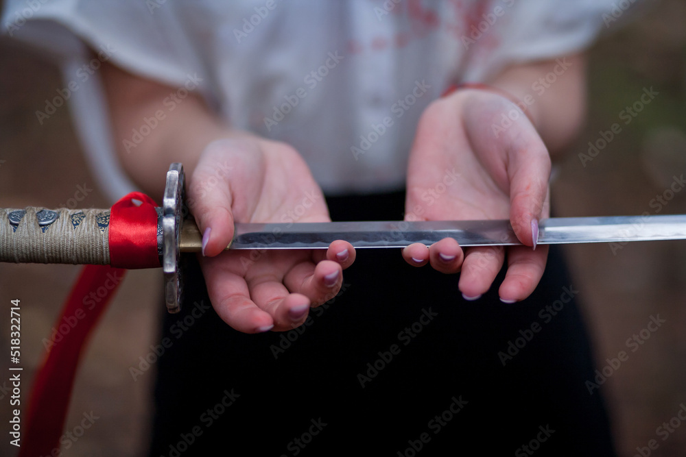 Japanese samurai sword katana with a red ribbon, stands near a tree, on ...