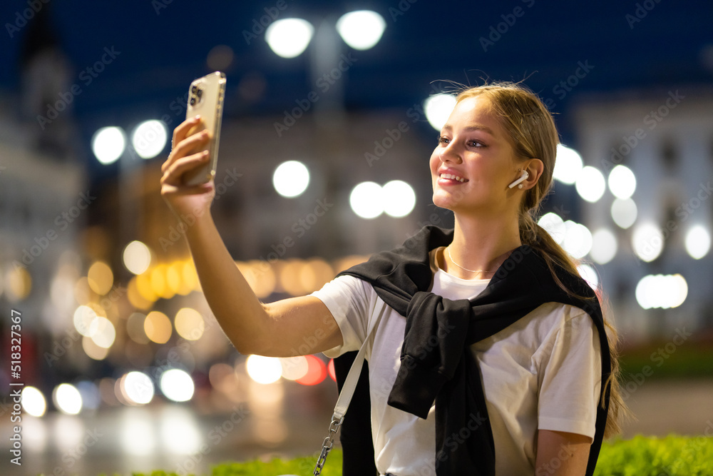 Young woman makes a video call when she is outside in the city at night ...