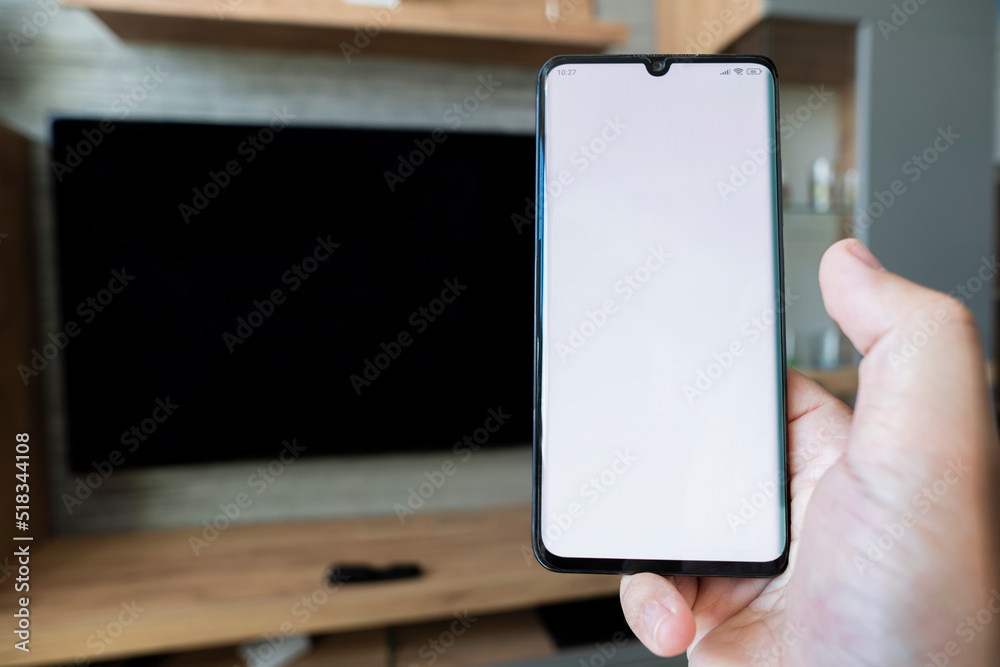 man hand tap on white screen smartphone with screen tv on background in ...
