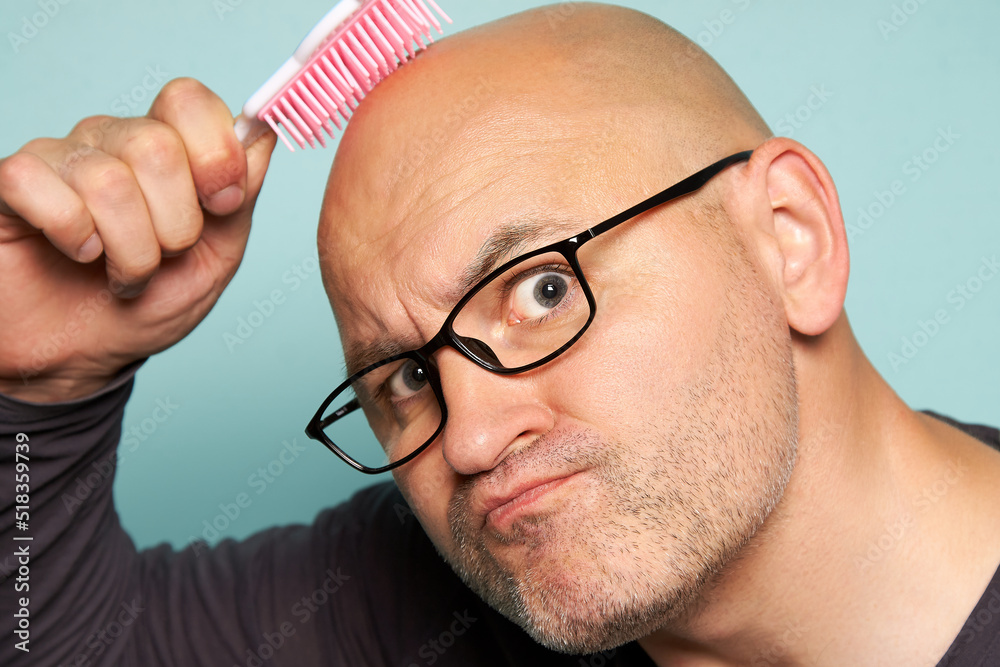 Bald bearded man with glasses is fooling around in front of the camera ...