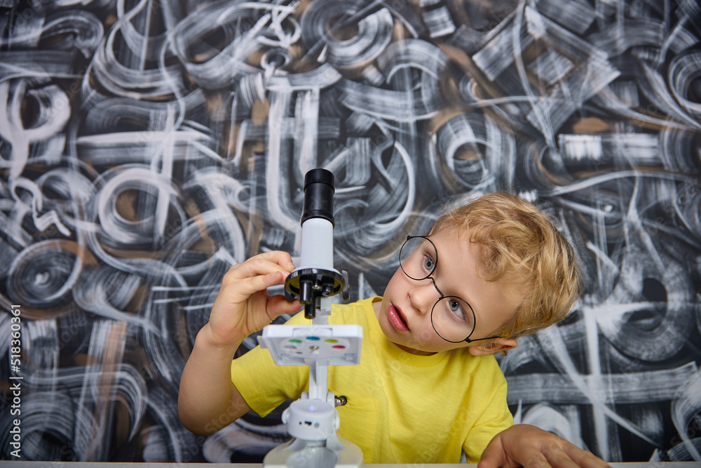 In a real lab class, a young child carefully examines a black and white ...