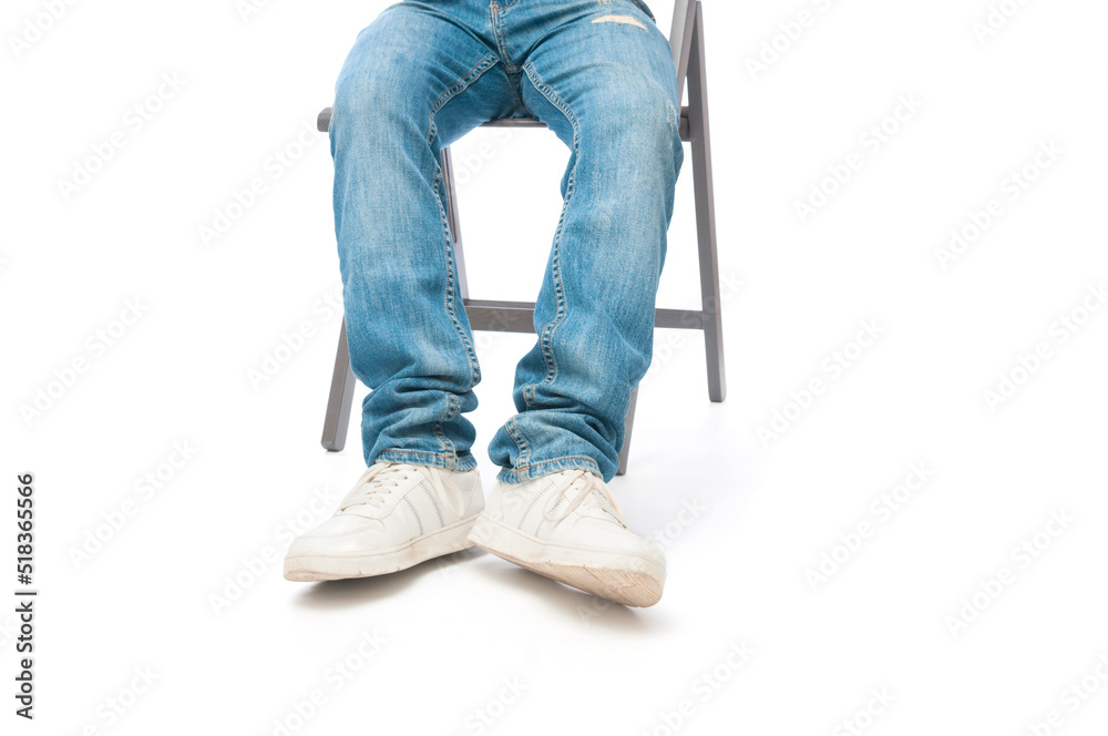 Legs of man with jeans and sneakers sitting on chair on white ...