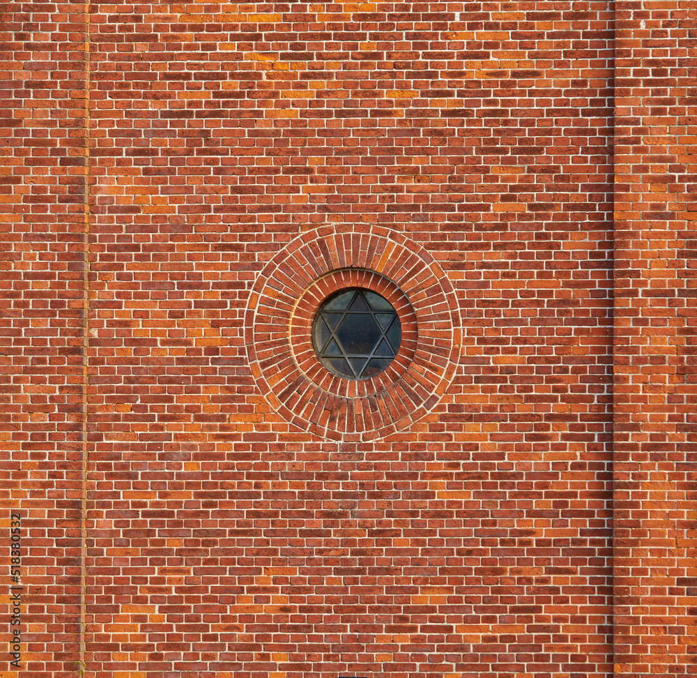 Wall of a jewish synagogue with round window on an old red brick house ...