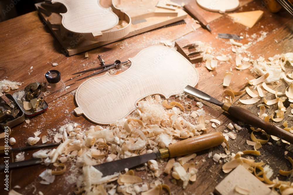 Luthier's work table full of wood shavings, tools and violin pieces ...