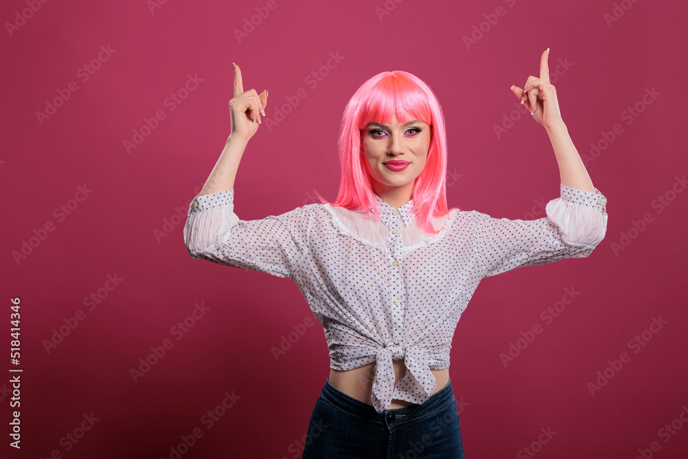Cheerful pretty model pointing up with index fingers in studio, posing ...