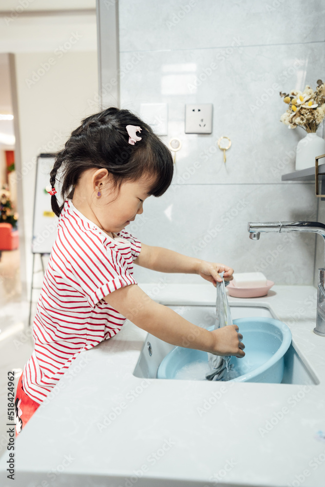 Cute little girl washing clothes in bathroom Stock Photo | Adobe Stock