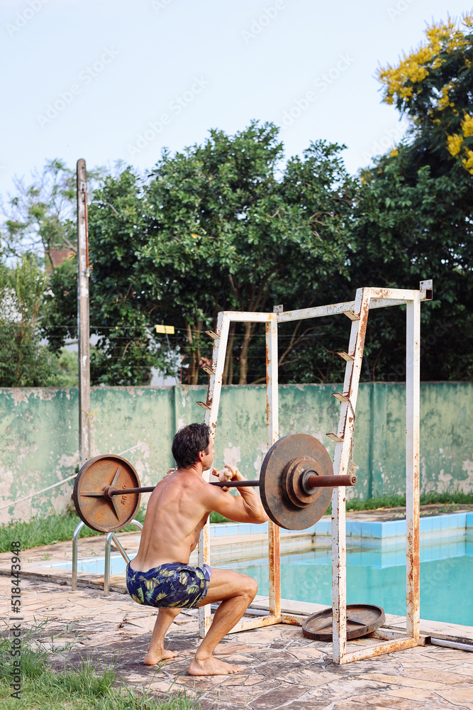 Bodybuilder squeeze a bar next to the pool Stock Photo | Adobe Stock